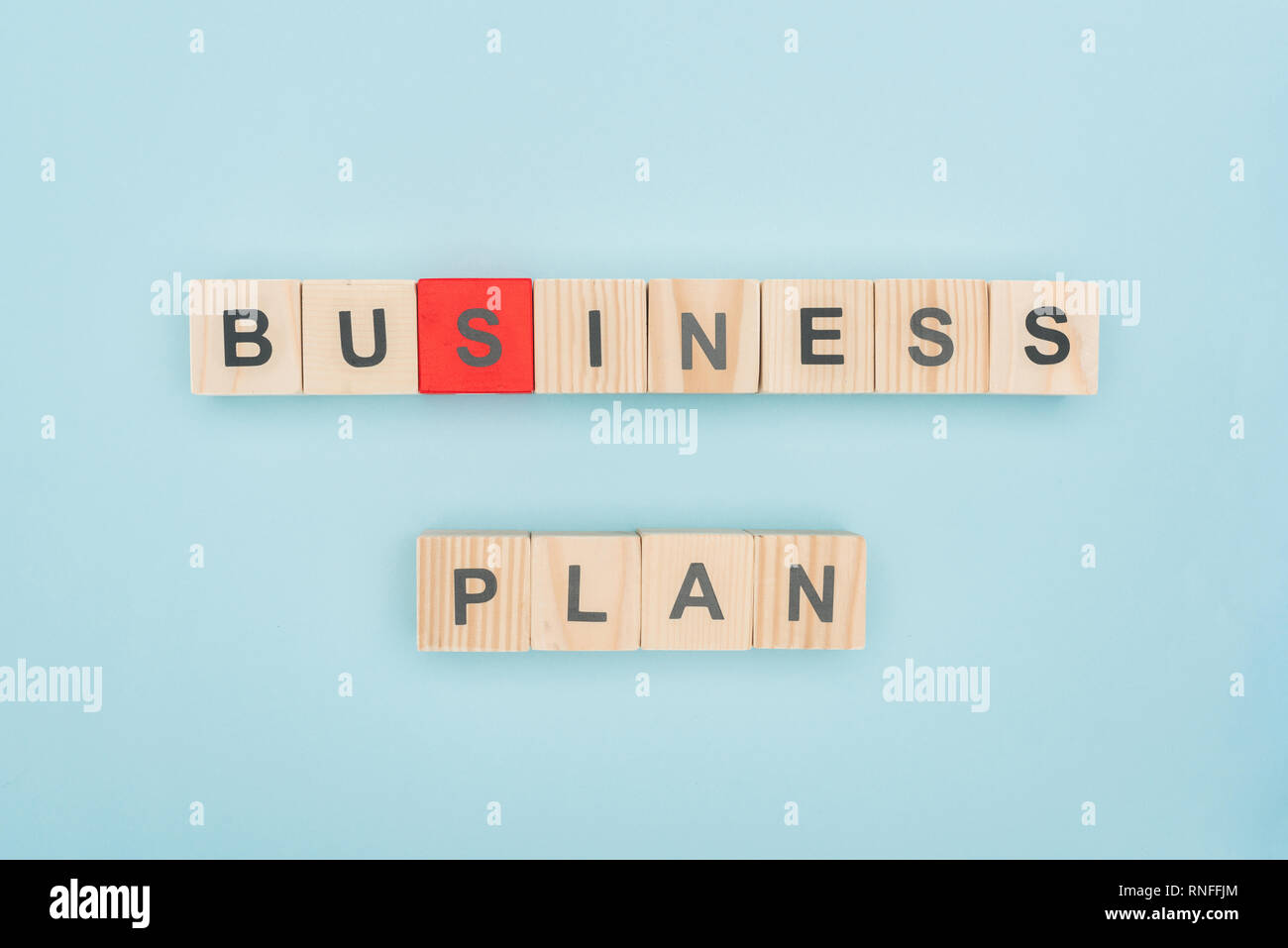 top view of business plan lettering made of wooden cubes on blue ...