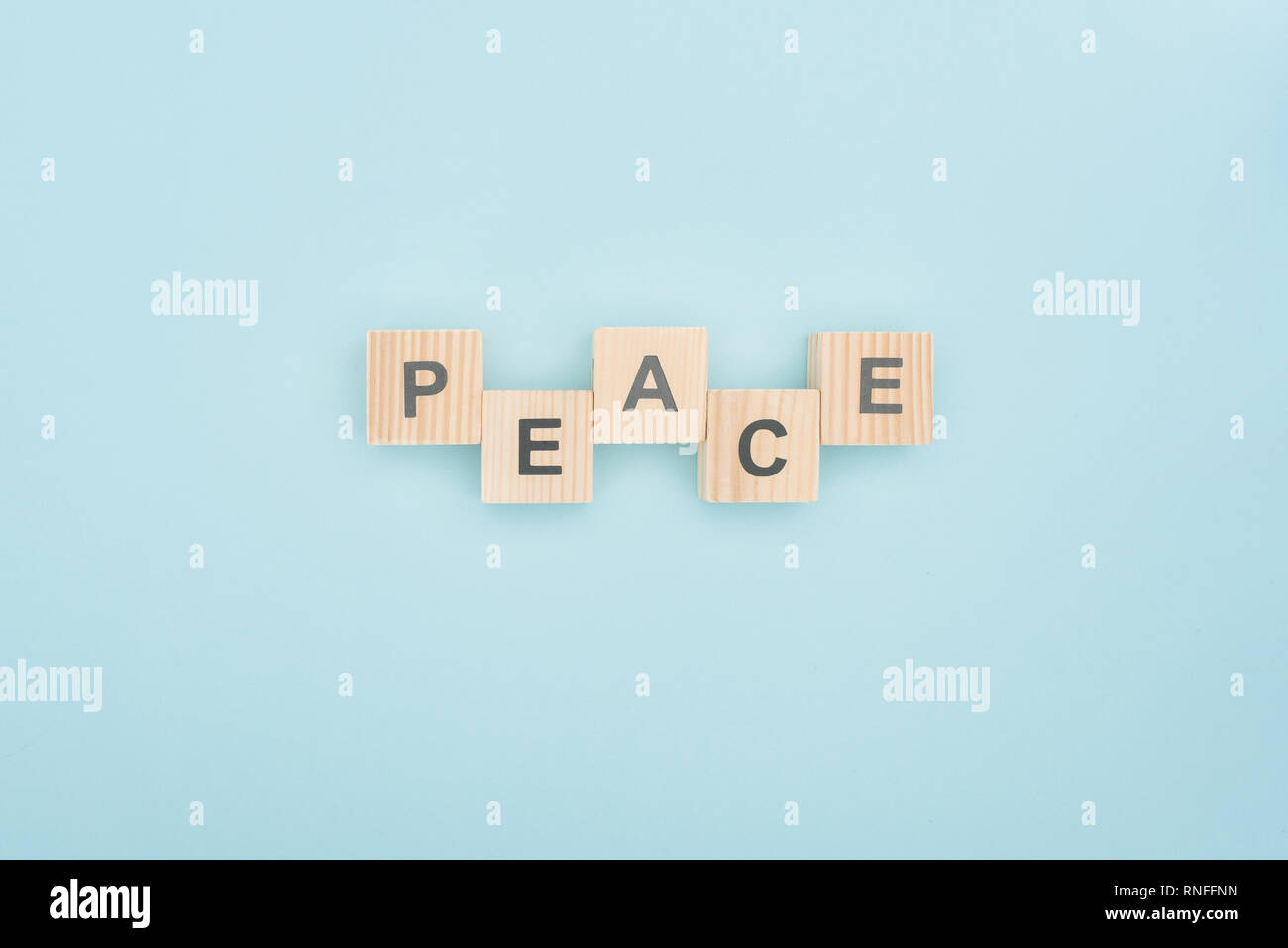 top view of peace lettering made of wooden blocks on blue background ...