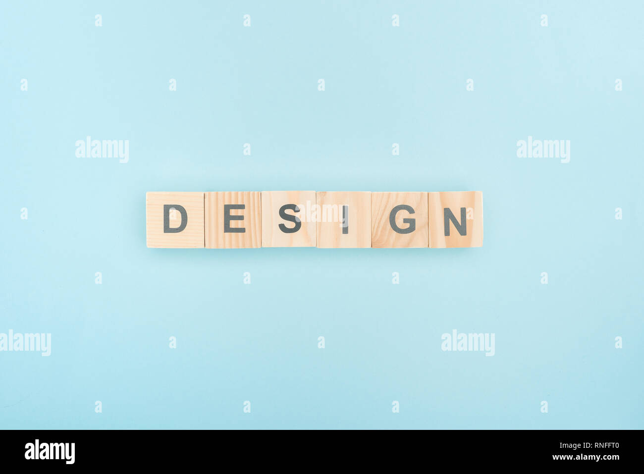 top view of design lettering made of wooden cubes on blue background ...