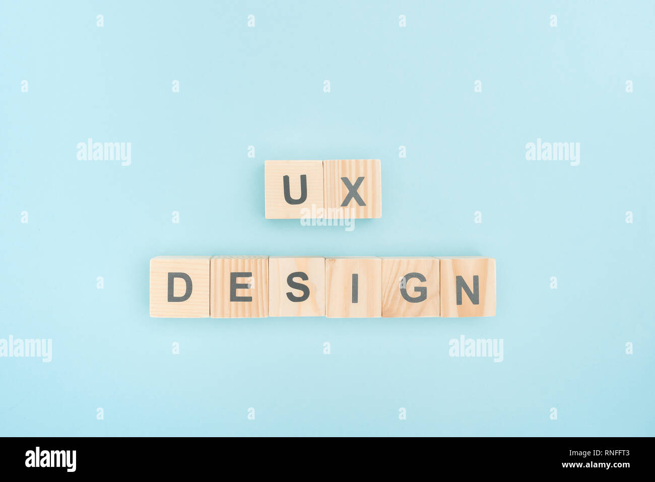 top view of ux design lettering made of wooden cubes on blue background ...