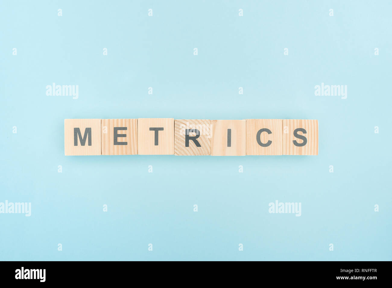 top view of metrics lettering made of wooden cubes on blue background ...