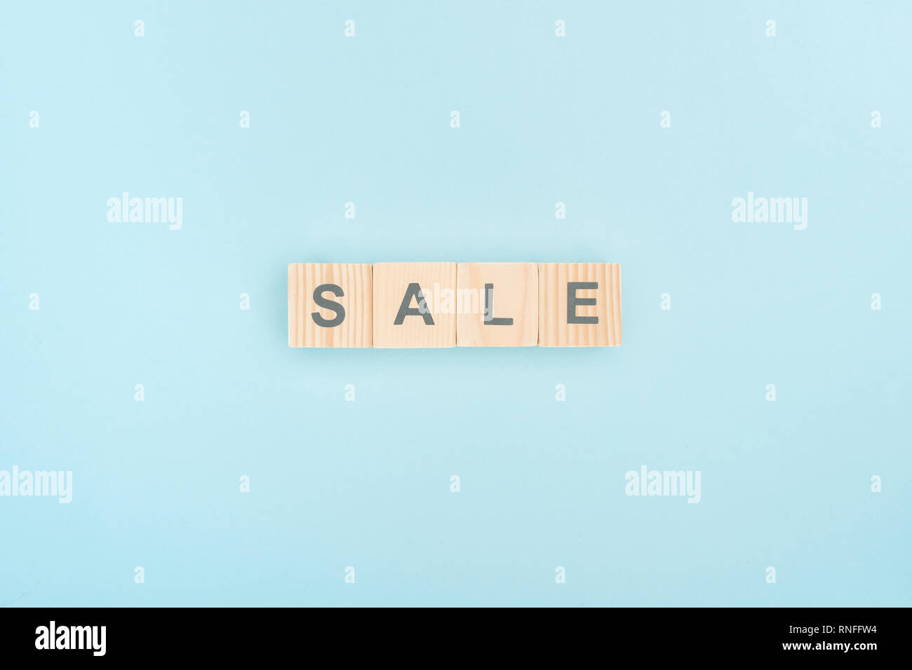 top view of sale lettering made of wooden cubes on blue background ...