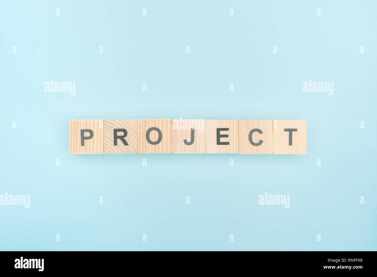 top view of project lettering made of wooden cubes on blue background ...