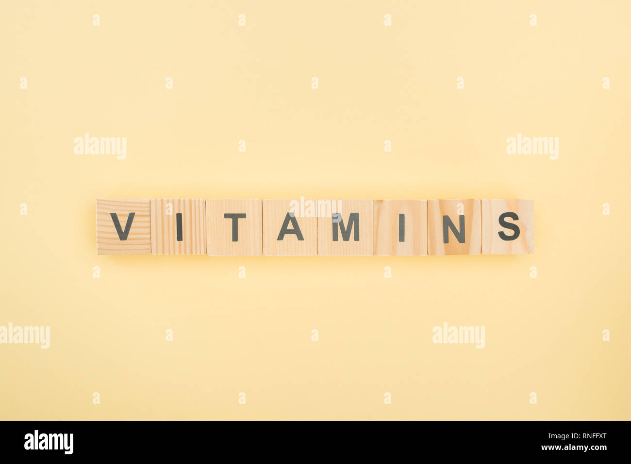 top view of vitamins lettering made of wooden cubes on yellow ...