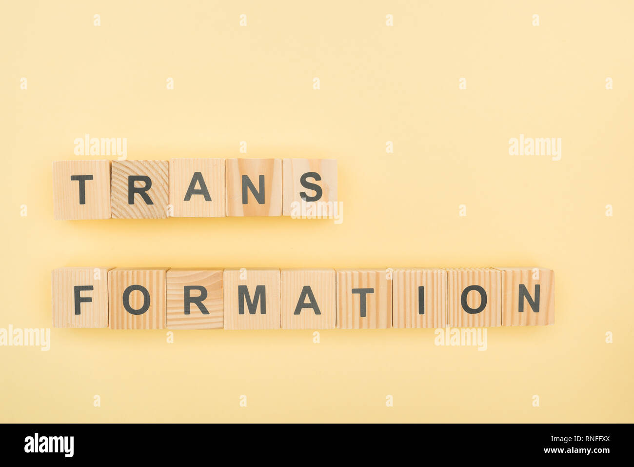 top view of transformation lettering made of wooden cubes on yellow ...