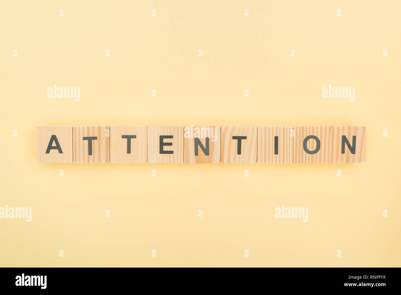 top view of attention lettering made of wooden cubes on yellow ...