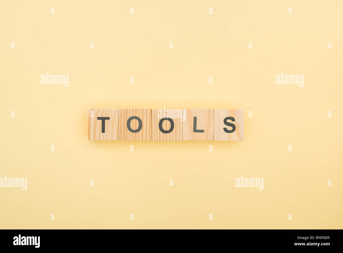top view of tools lettering made of wooden cubes on yellow background ...