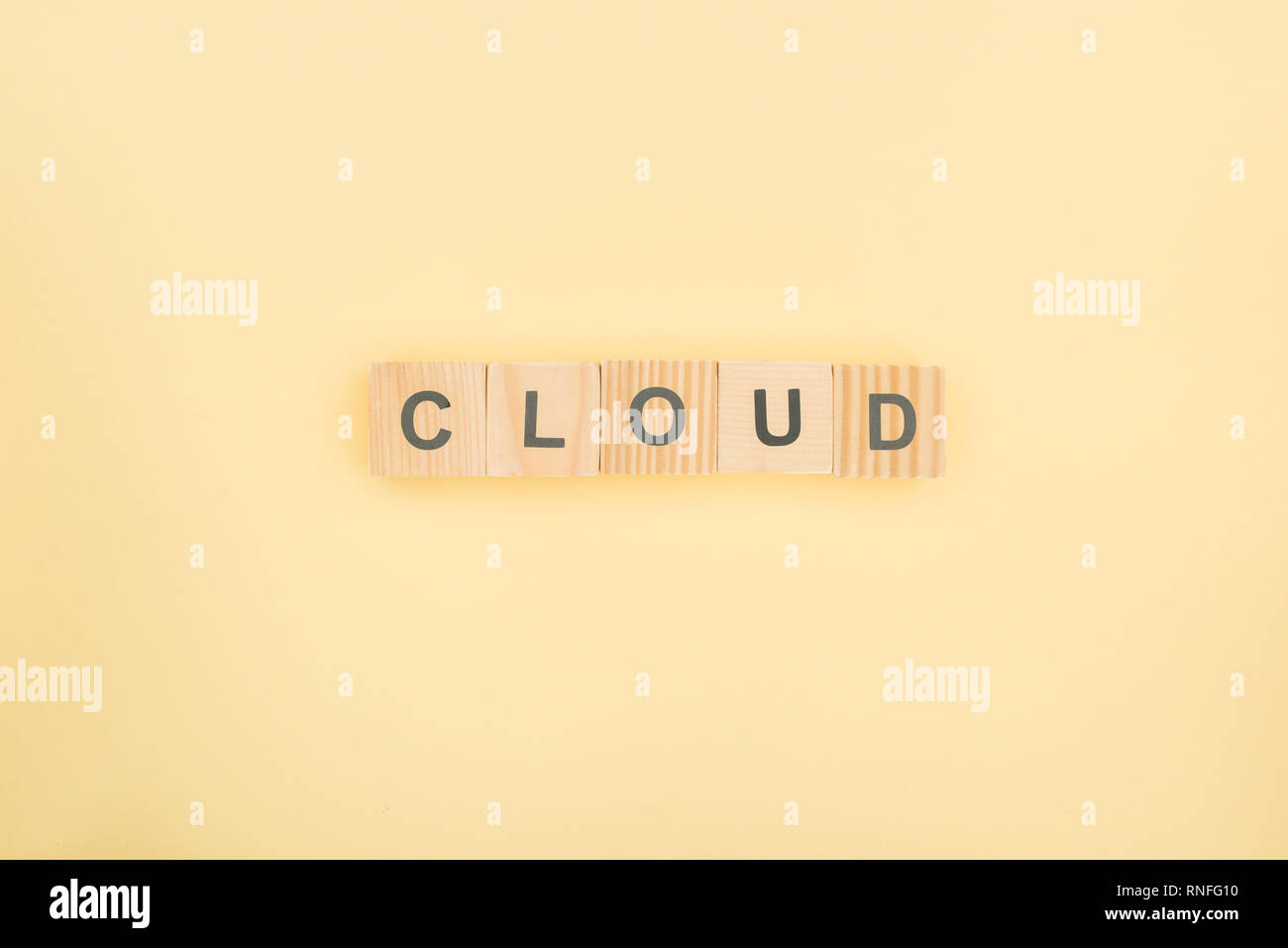 top view of cloud lettering made of wooden cubes on yellow background ...