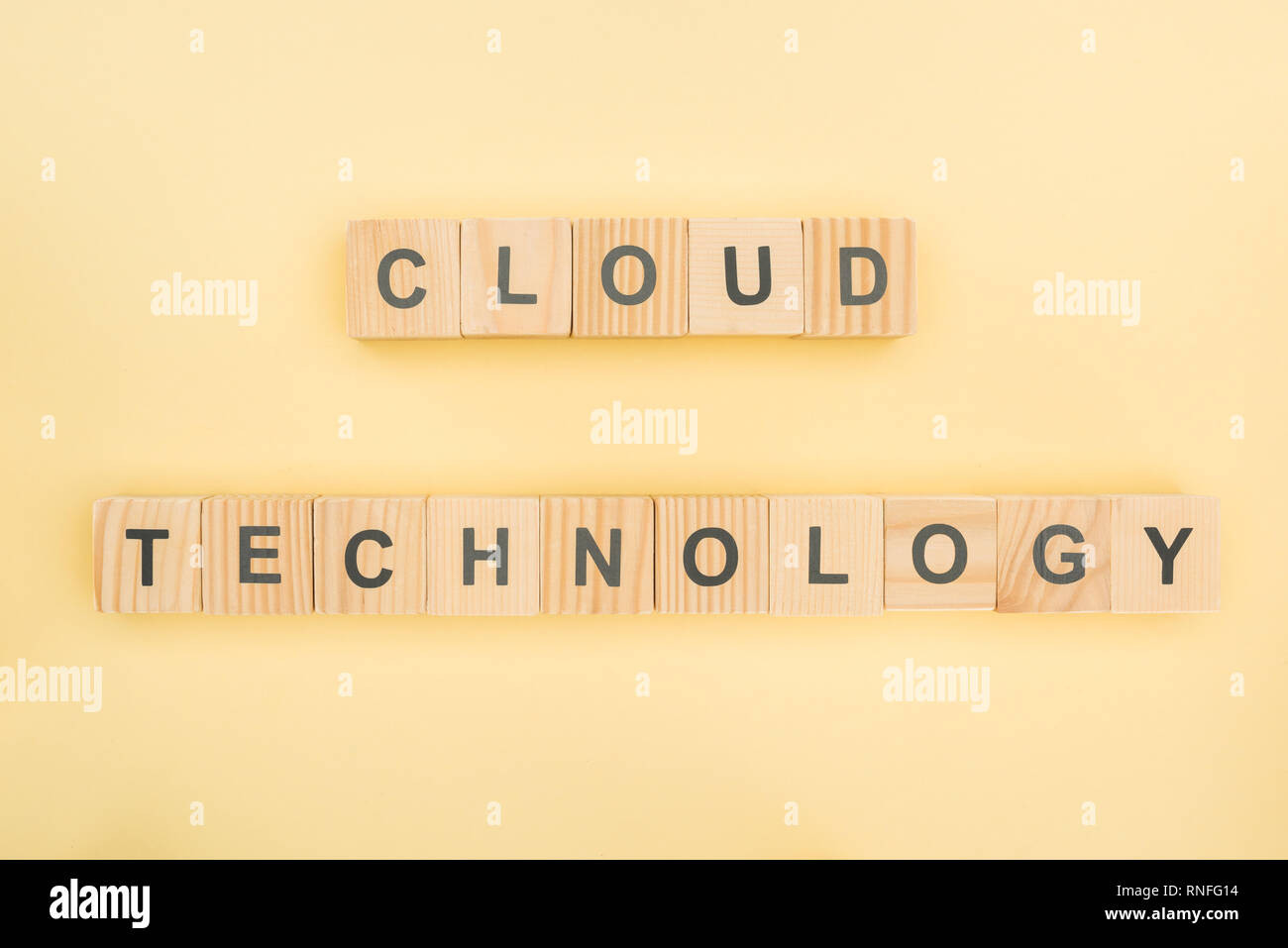 top view of cloud technology lettering made of wooden cubes on yellow ...