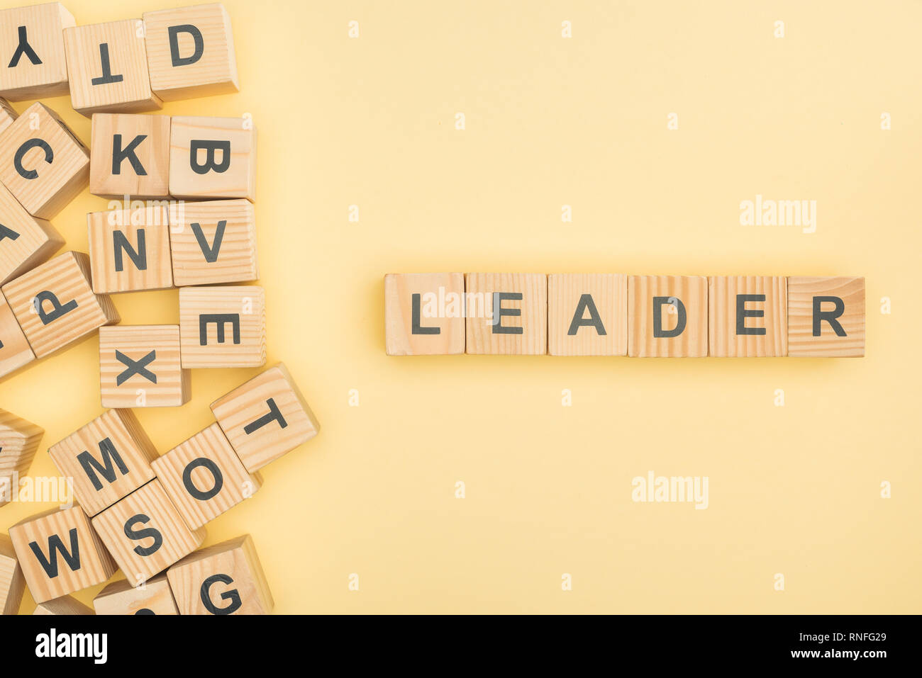 top view of leader lettering with wooden cubes on yellow background ...