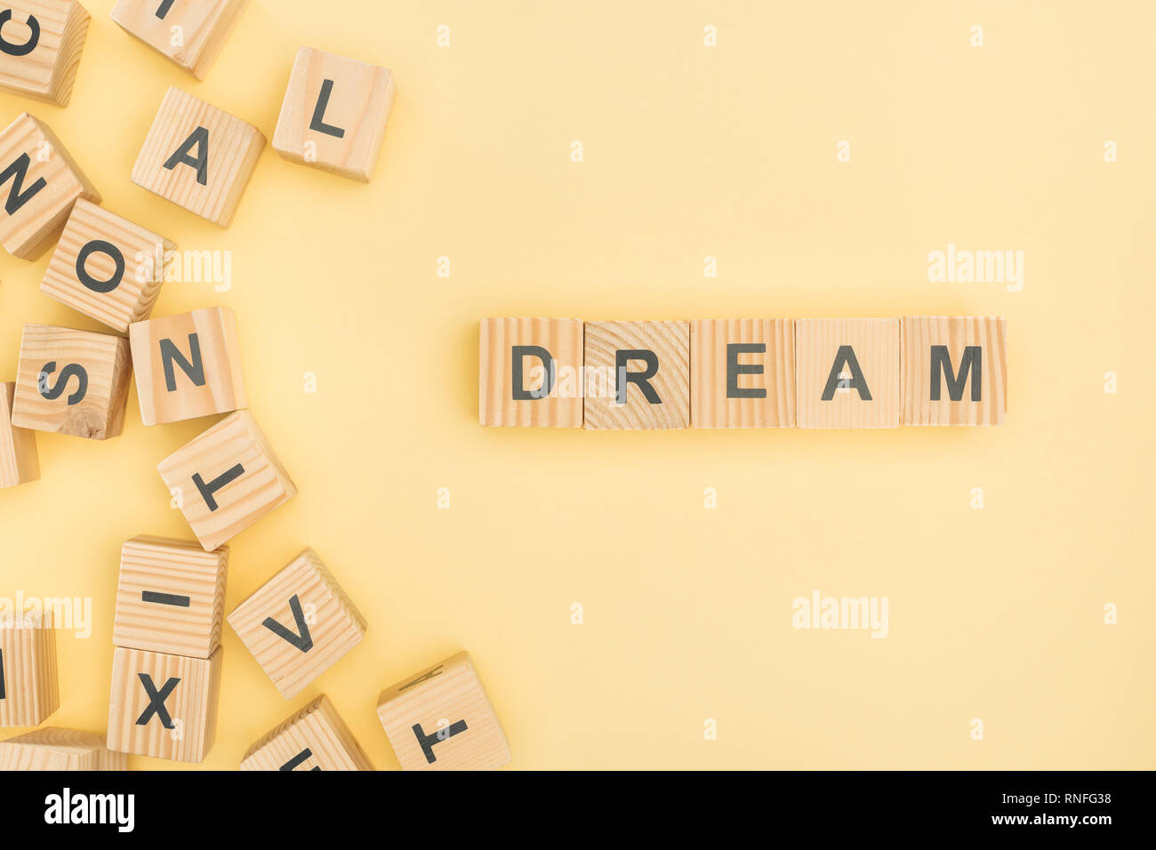 top view of dream lettering with wooden cubes on yellow background ...