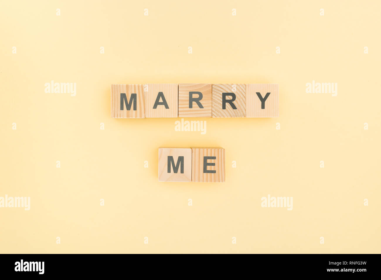 top view of marry me lettering made of wooden blocks on yellow ...
