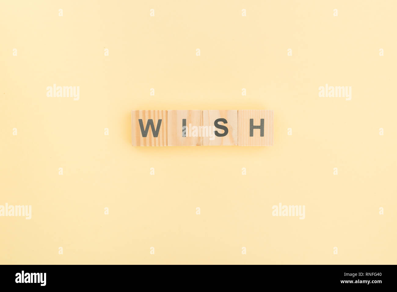 top view of wish lettering made of wooden blocks on yellow background ...