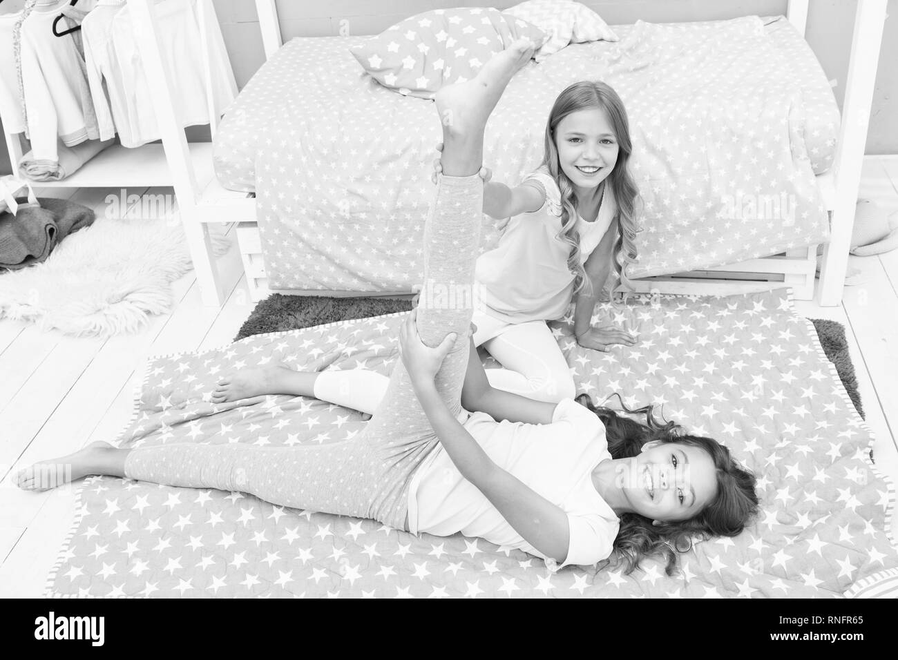 Girl child sit split in bedroom. Friends gymnasts support each other ...