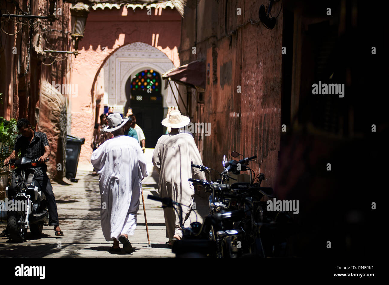 A couple men in their thawb or djellaba, traditional tunics, walk ...