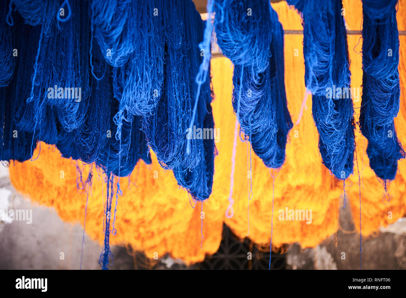 Bundles of wool string hang from bamboo poles overhead to dry in the ...