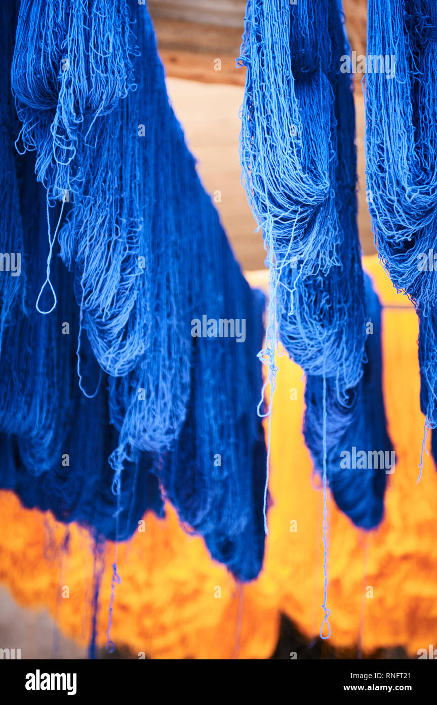 Bundles of wool string hang from bamboo poles overhead to dry in the ...