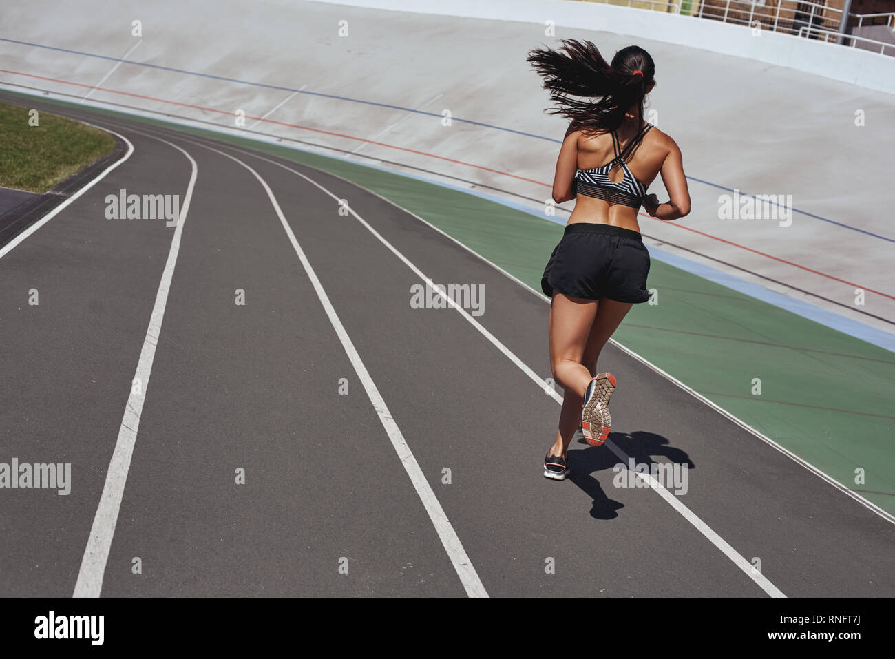 Young woman wearing black sportswear running on racetrack during ...
