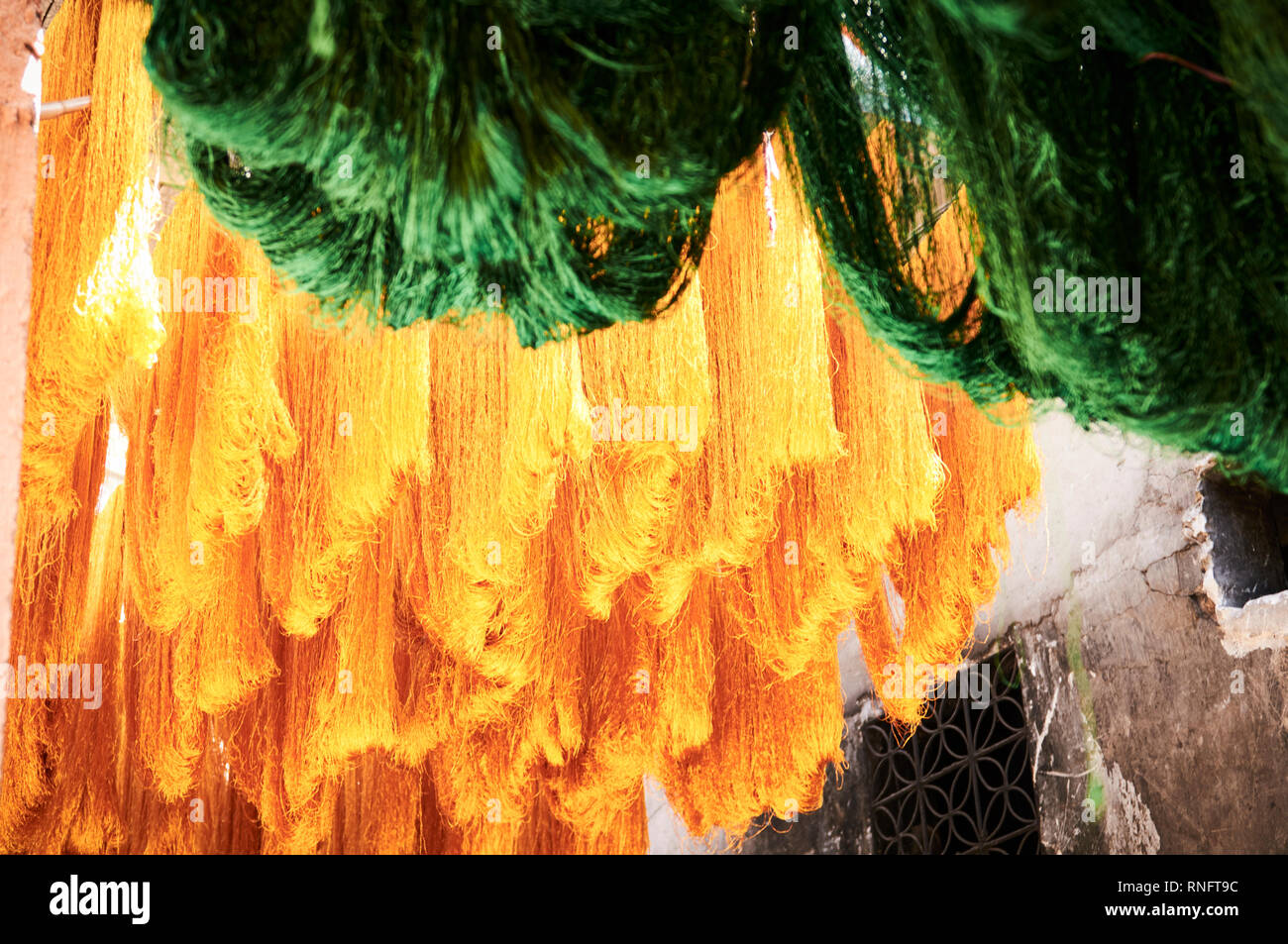 Bundles of wool string hang from bamboo poles overhead to dry in the ...