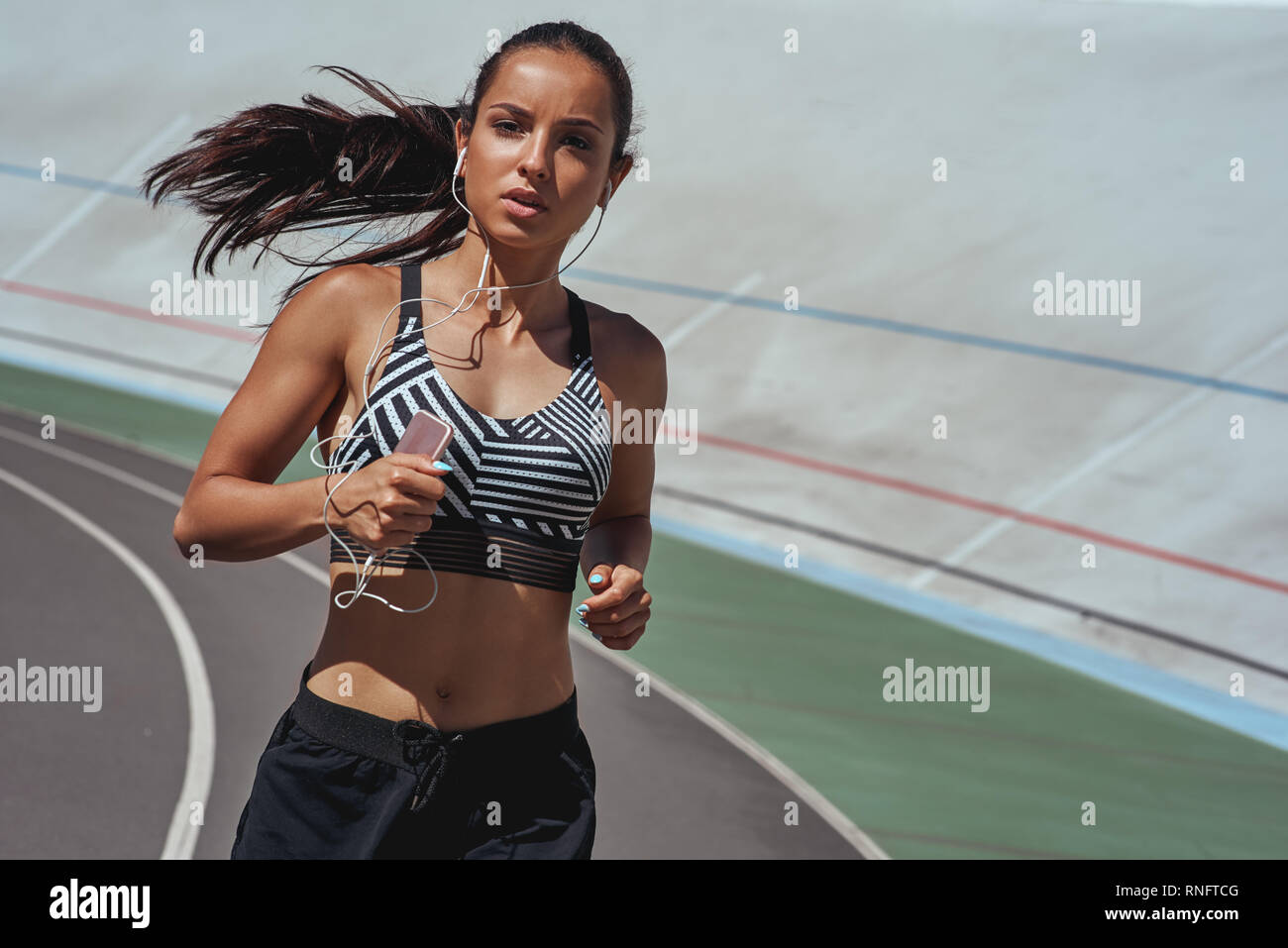 Full-length portrait of young woman wearing black sportswear running on ...