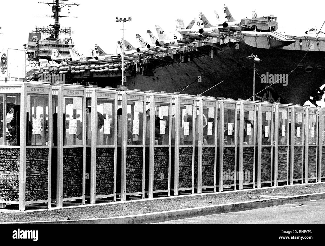 Sailors use some of the telephone booths on the pier beside the ...