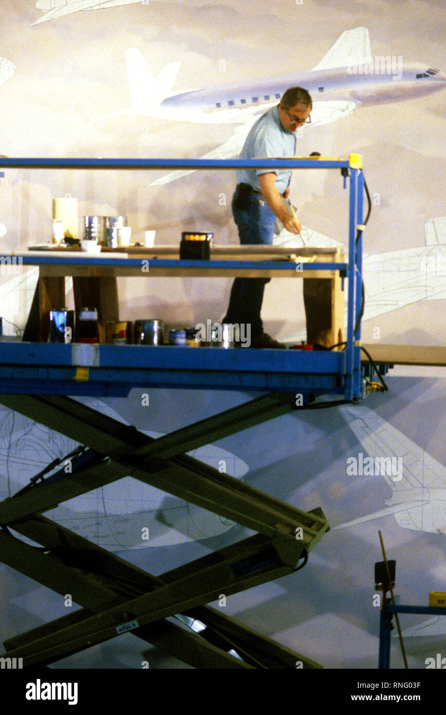 An aviation artist, paints a mural picture of aircraft, in flight, at ...