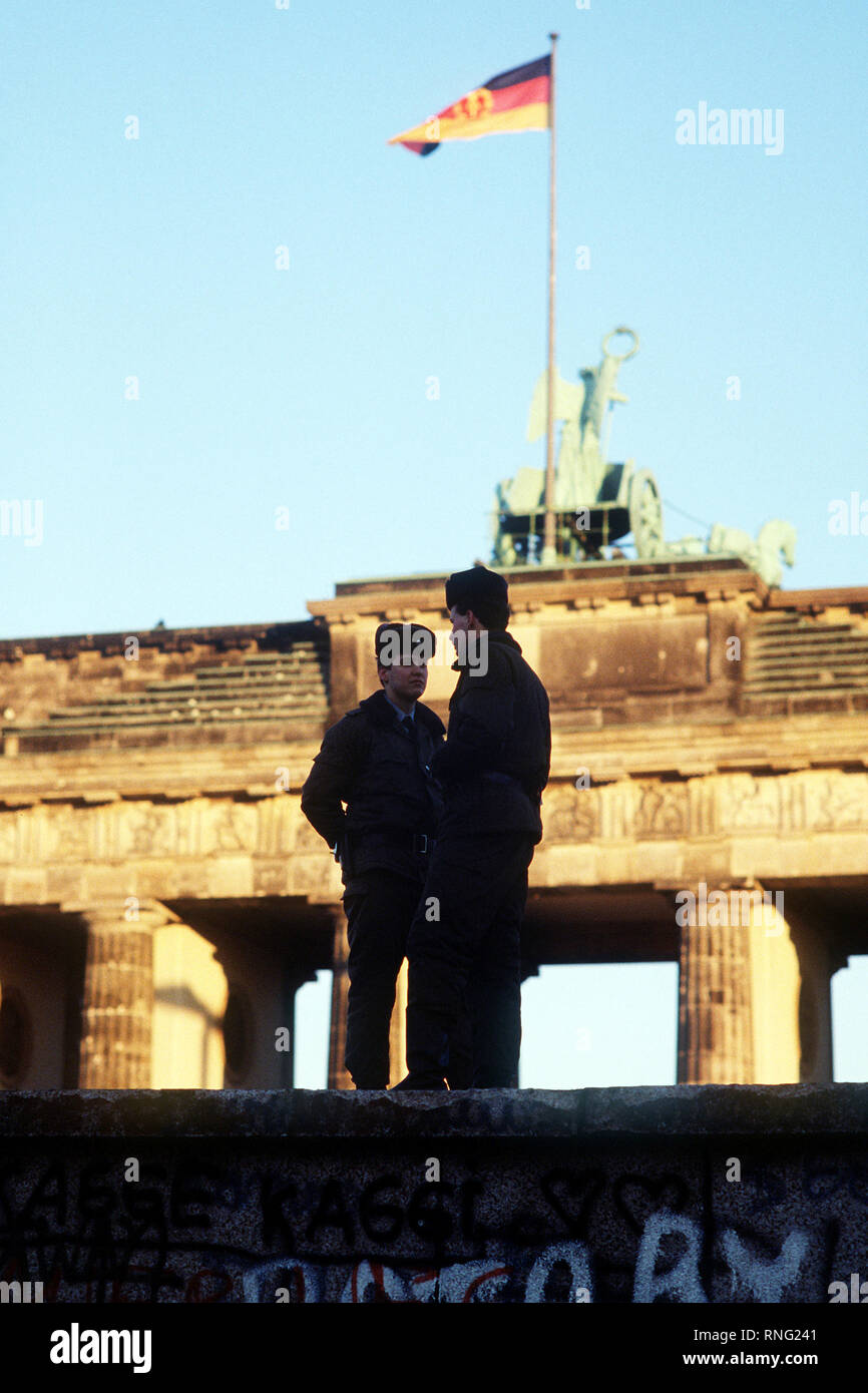 East German guards stand atop the Berlin Wall beside the Brandenburg ...