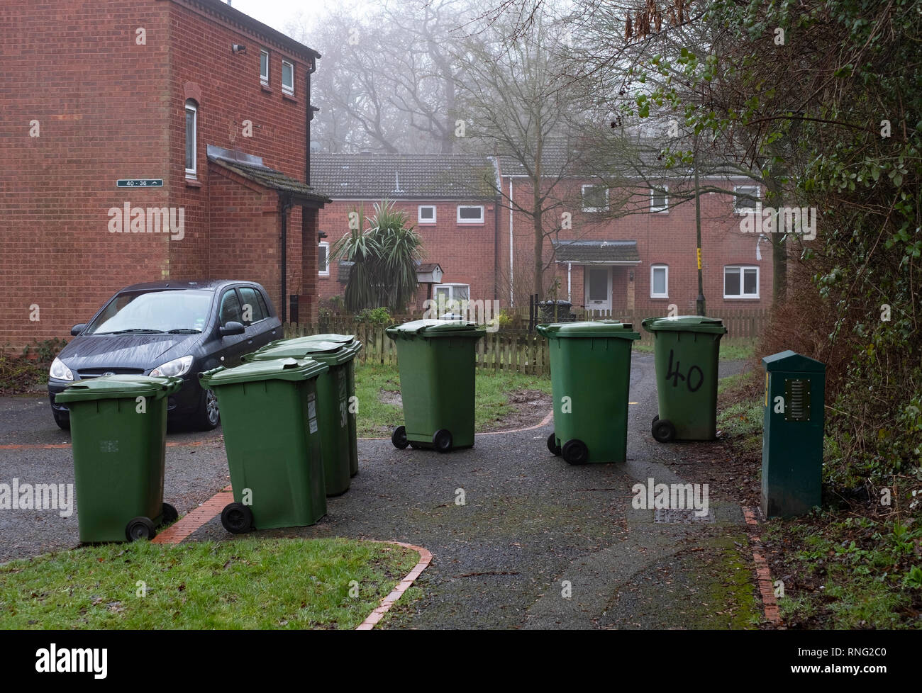 Green recycling dustbins wait to be collected and emptied on a housing ...