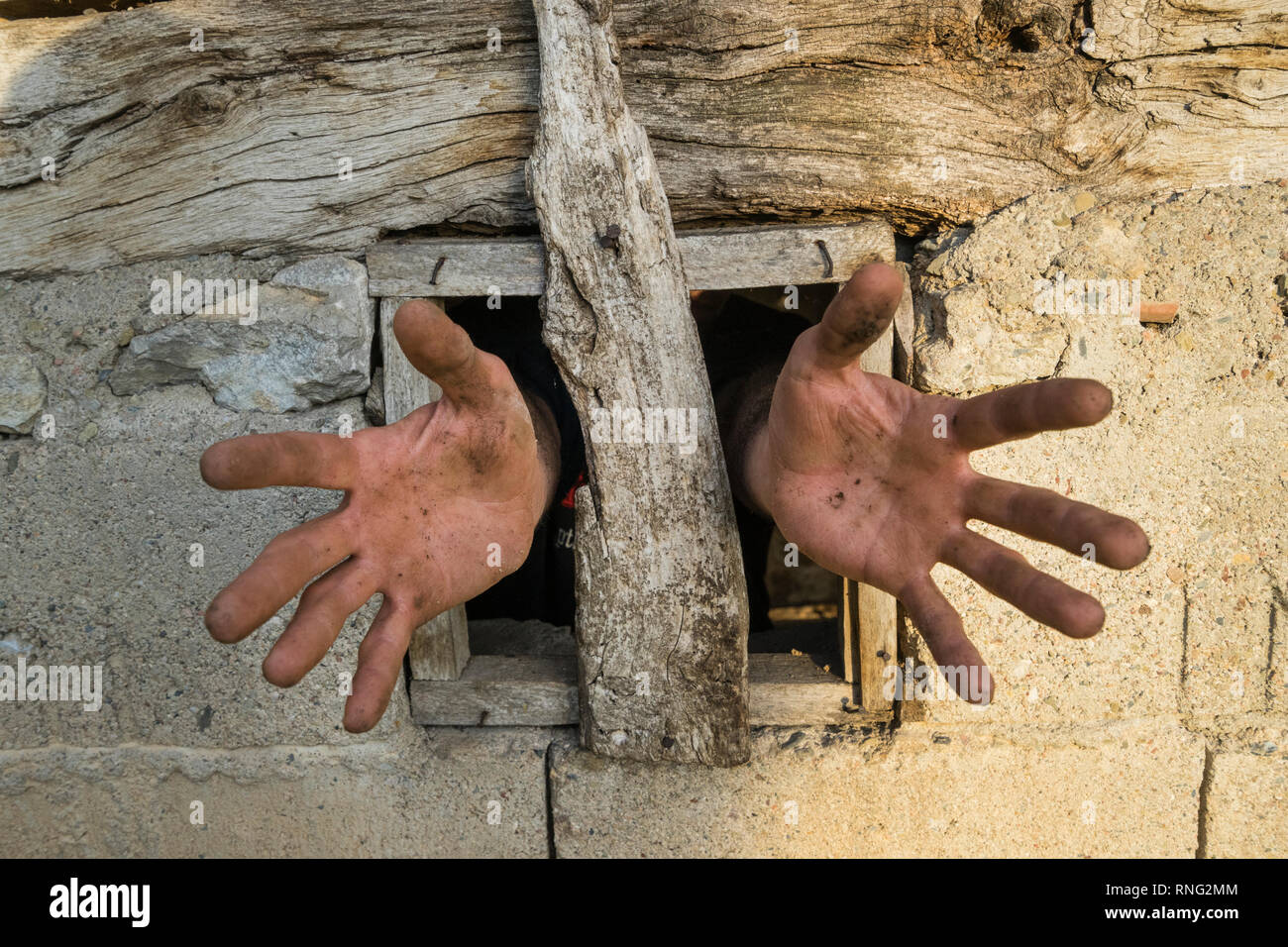 Hands reaching out of a small window from a mud and stone made house in ...