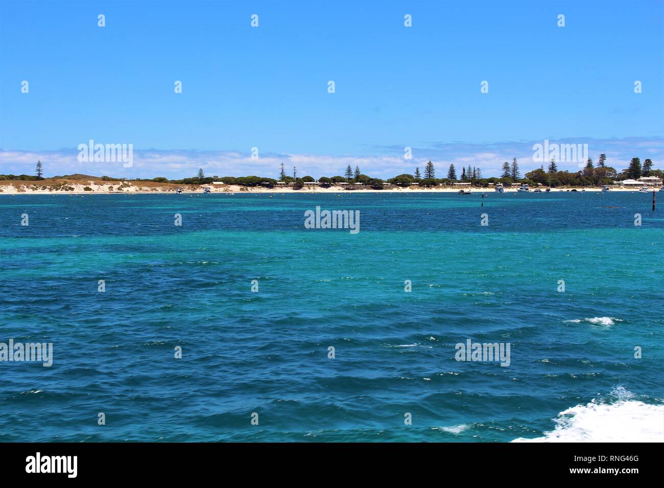 Clear blue sea with beach and trees on the horizon and a clear blue sky ...