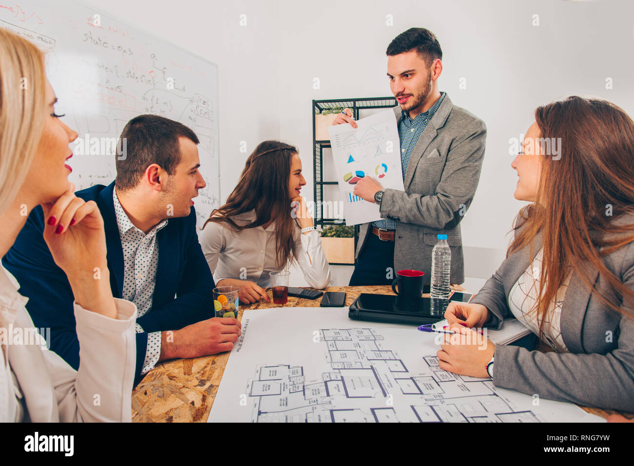A young working man is showing diagram presentation to his colleagues ...