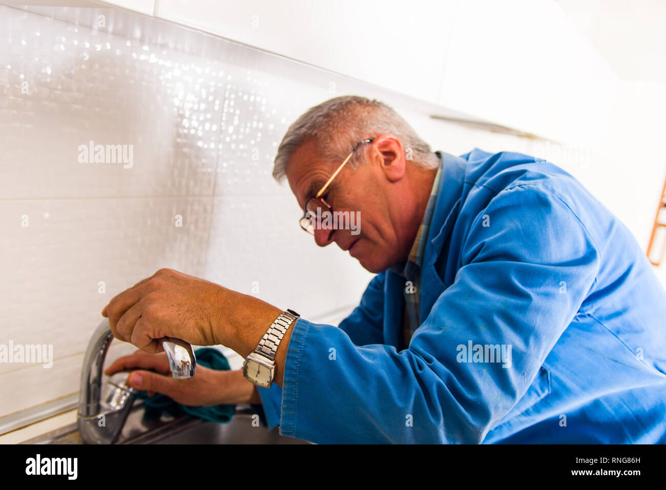 Professional old handyman is fixing the kitchen faucet Stock Photo - Alamy