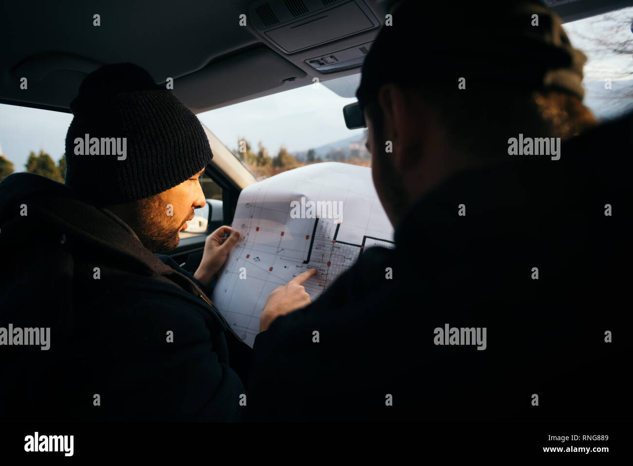 Two robbers planning and pointing on the blueprint(map) their objective ...