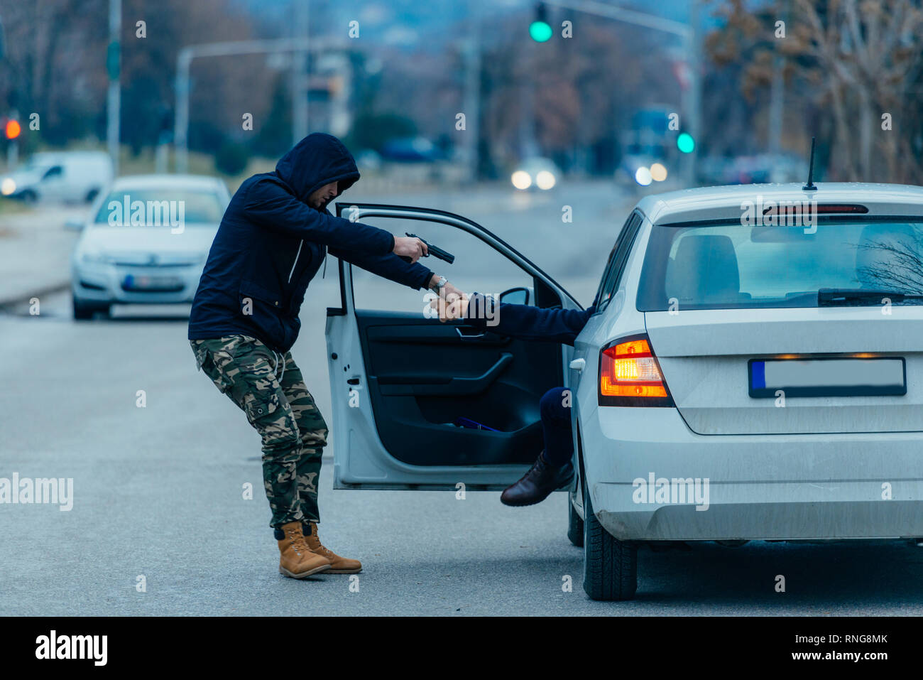 The car thief is pulling the car owner out of his car and trying to get ...