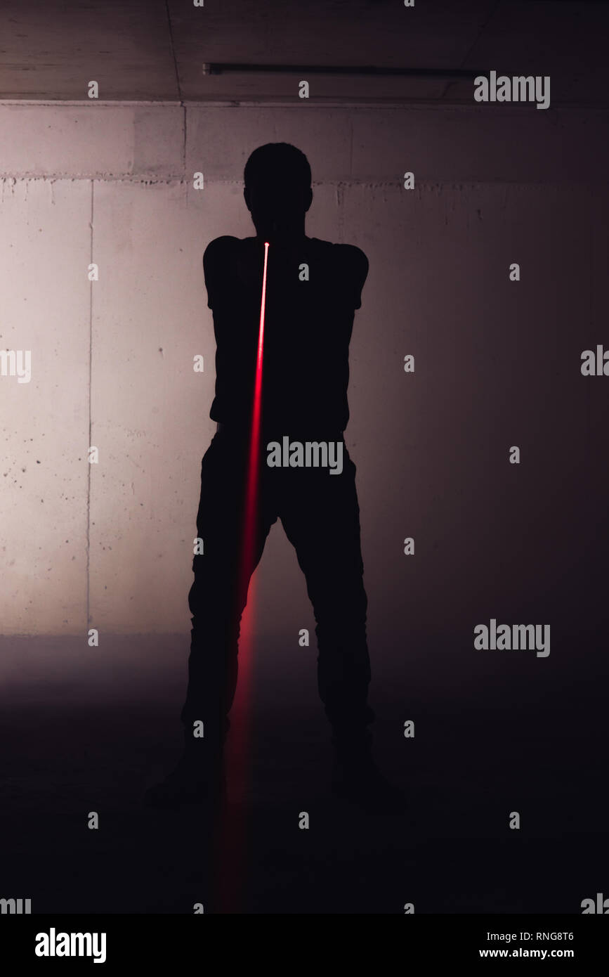 silhouette of an armed man holding his gun and pointing with his laser ...