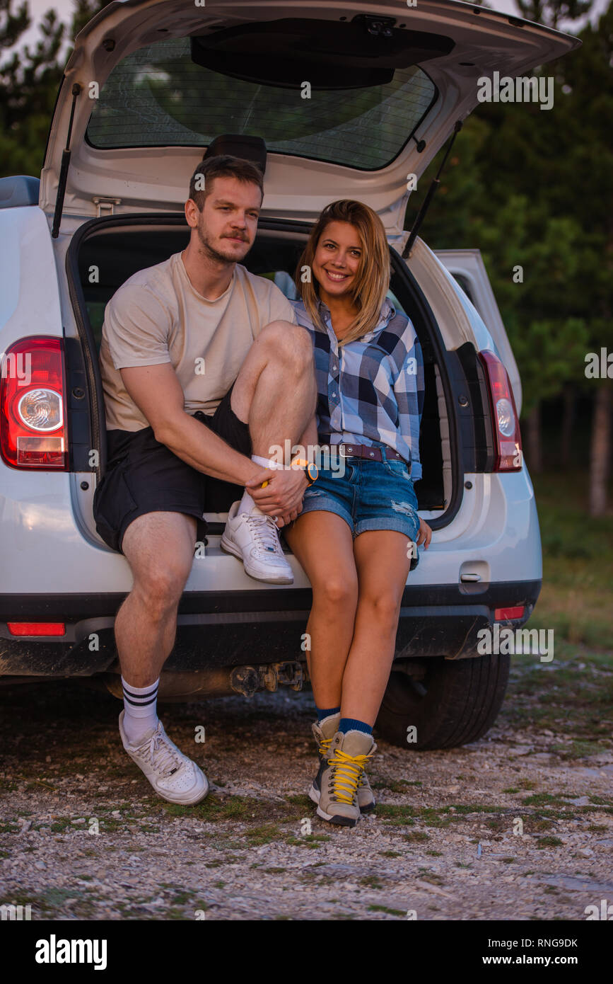 Young couple sitting on the back of a off road vehicle and enjoying the ...