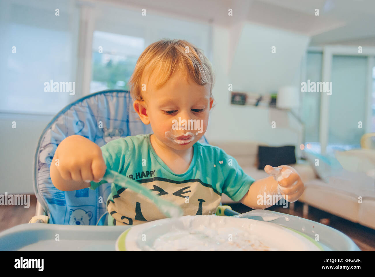 Smiling cute baby kid boy eating itself with spoon Stock Photo - Alamy