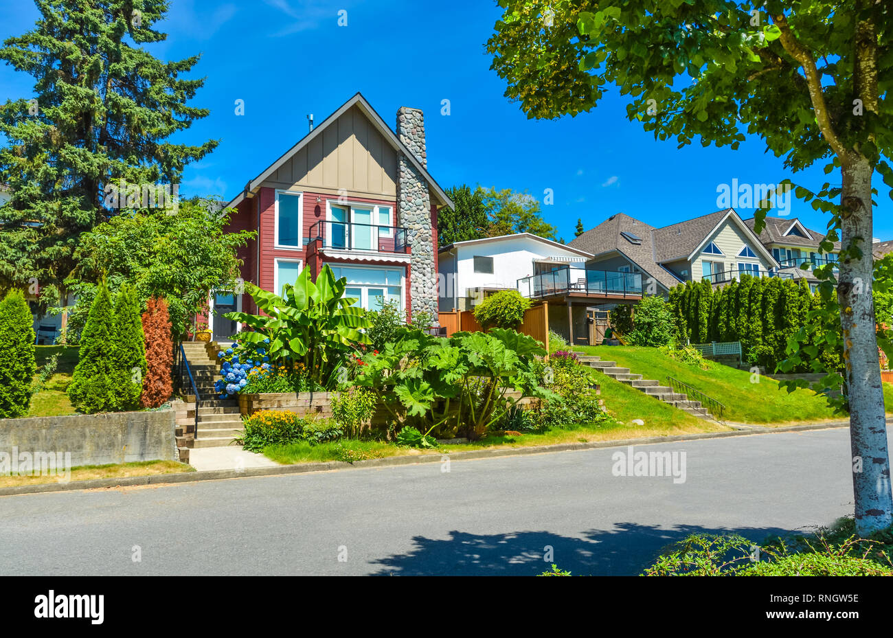 Beautiful suburban house with landscaped terraces and blue sky ...