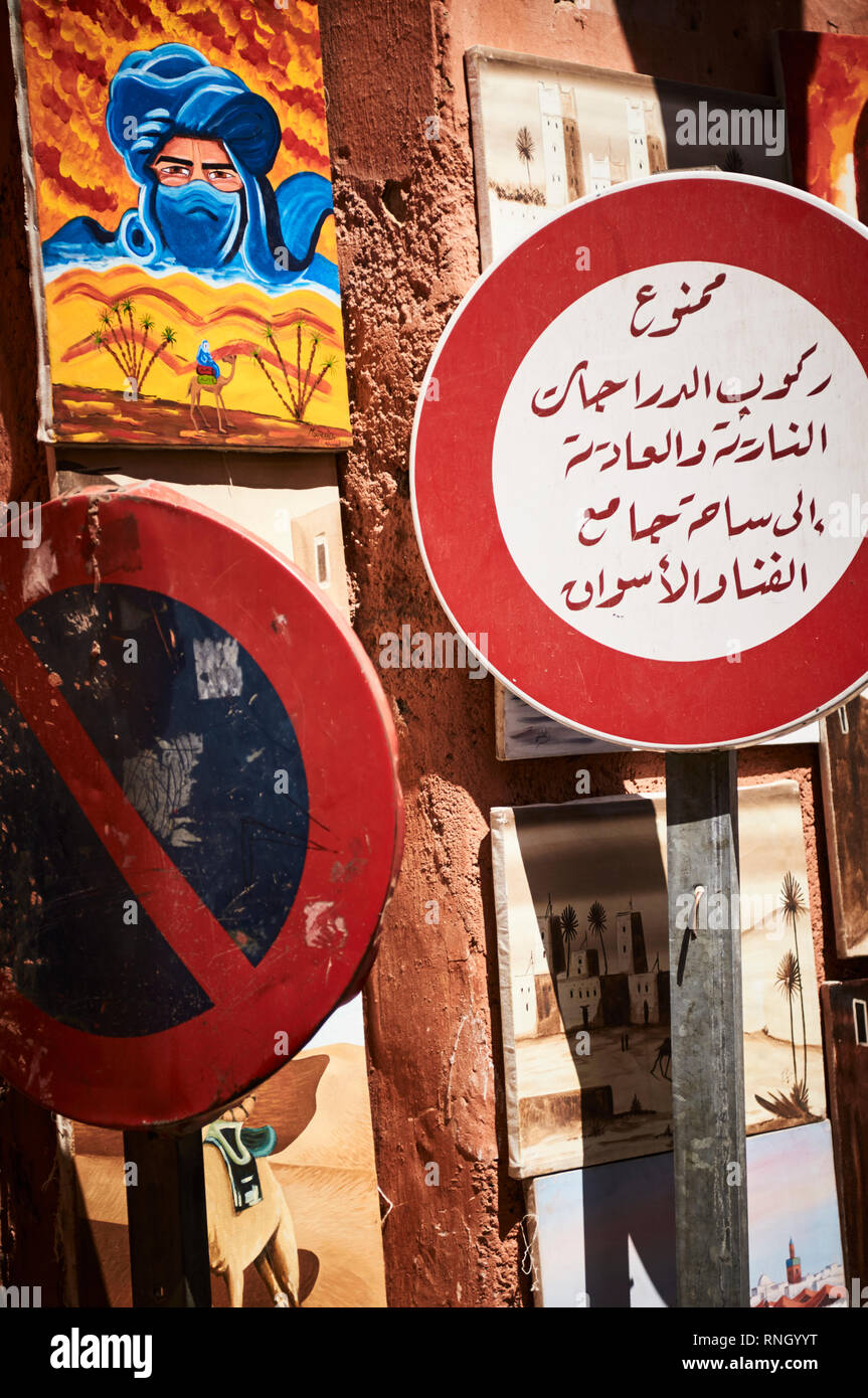 Beautiful dessert artwork is sold behind a cluster of street signs with ...