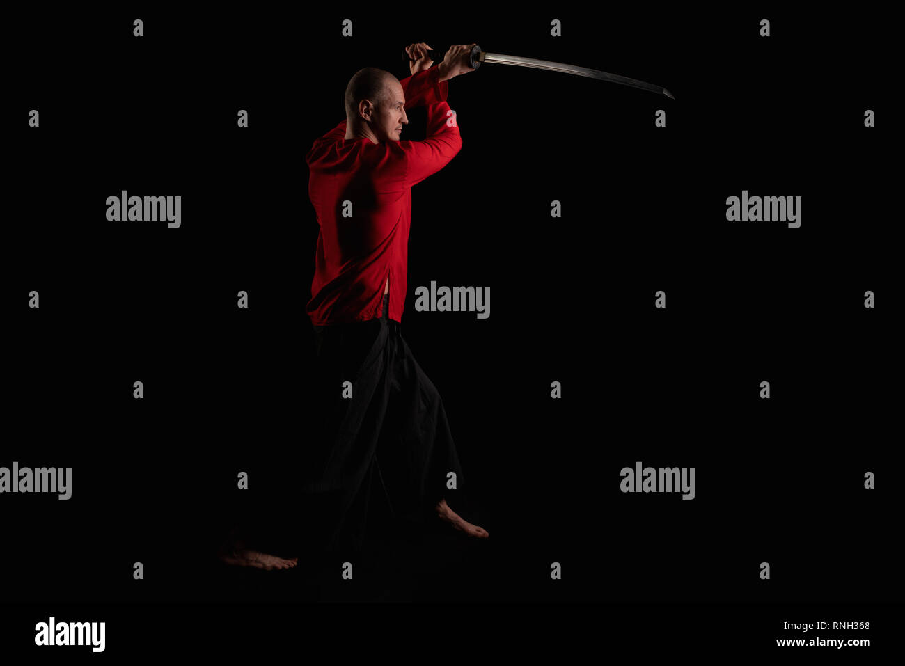 Male in red shirt doing exercises with a sword Stock Photo - Alamy