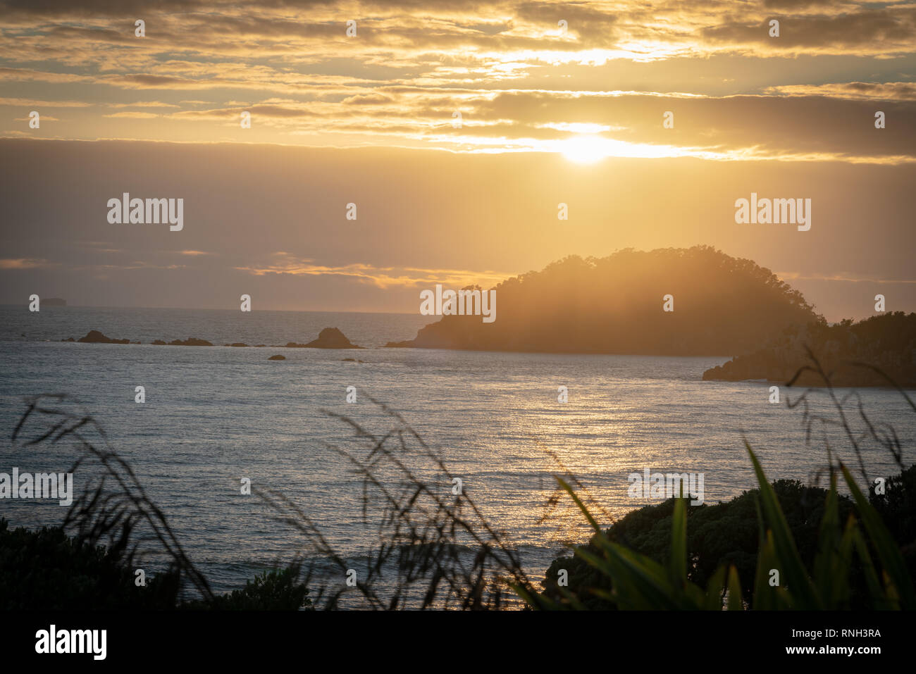 Golden sky and light as sun rises over Moturiki Island and Mount ...