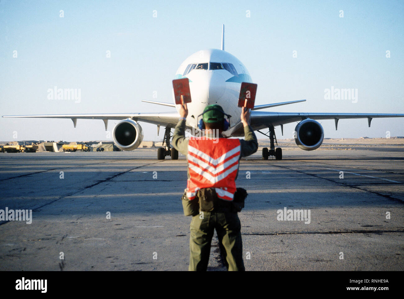 1981 - A ground crewman signals to a DC-10 aircraft landing to unload ...