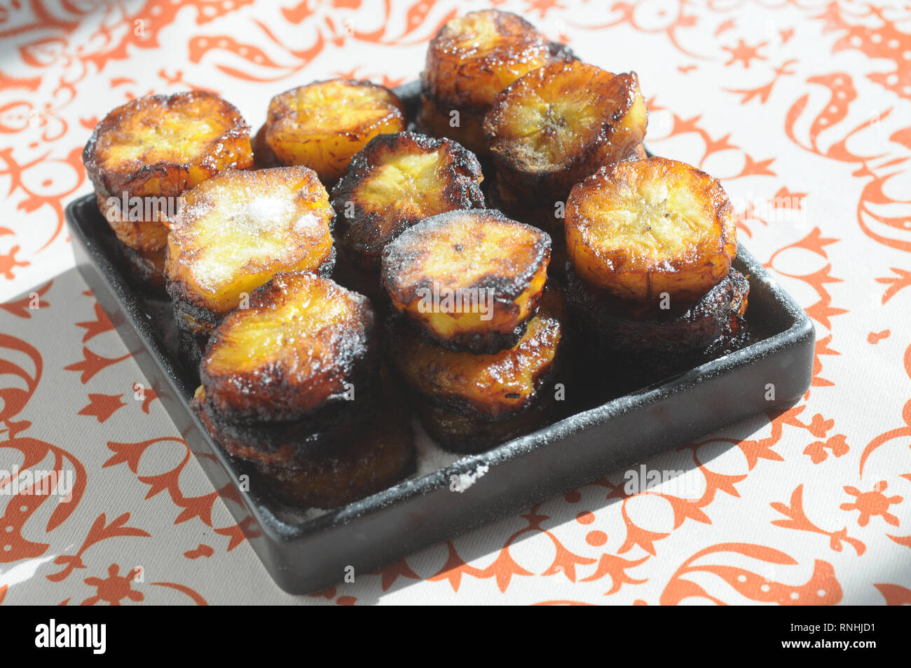 Fried plantains on a black plate Stock Photo - Alamy