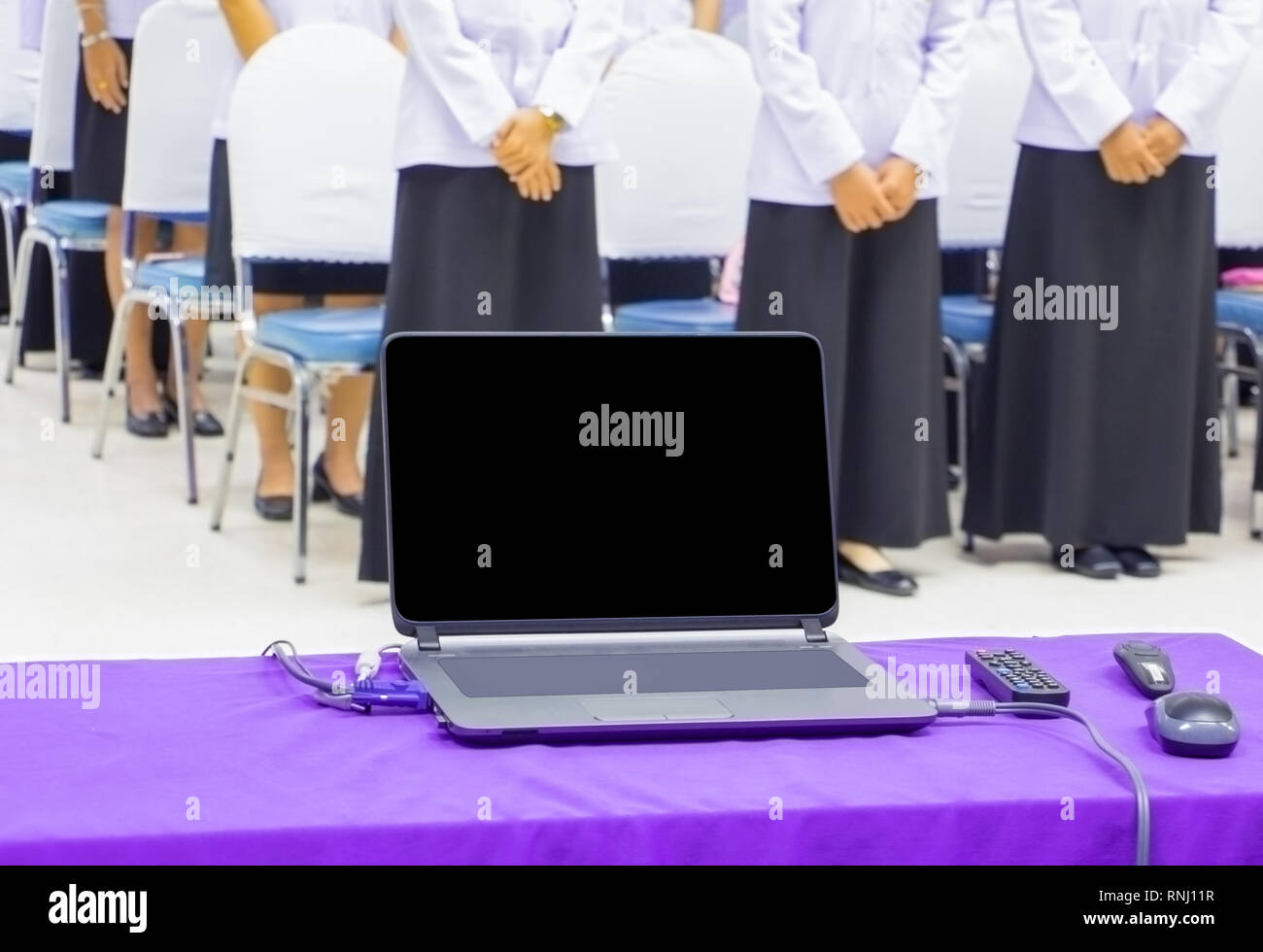 computer on the table purple fabric and group students blur in the a ...