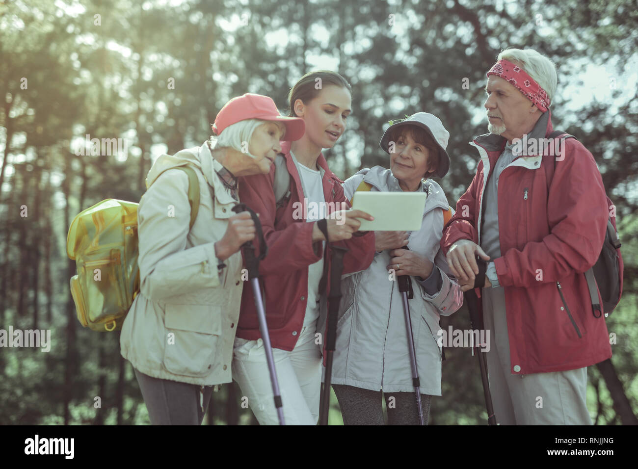 Group of tourists using interactive map for hiking Stock Photo - Alamy