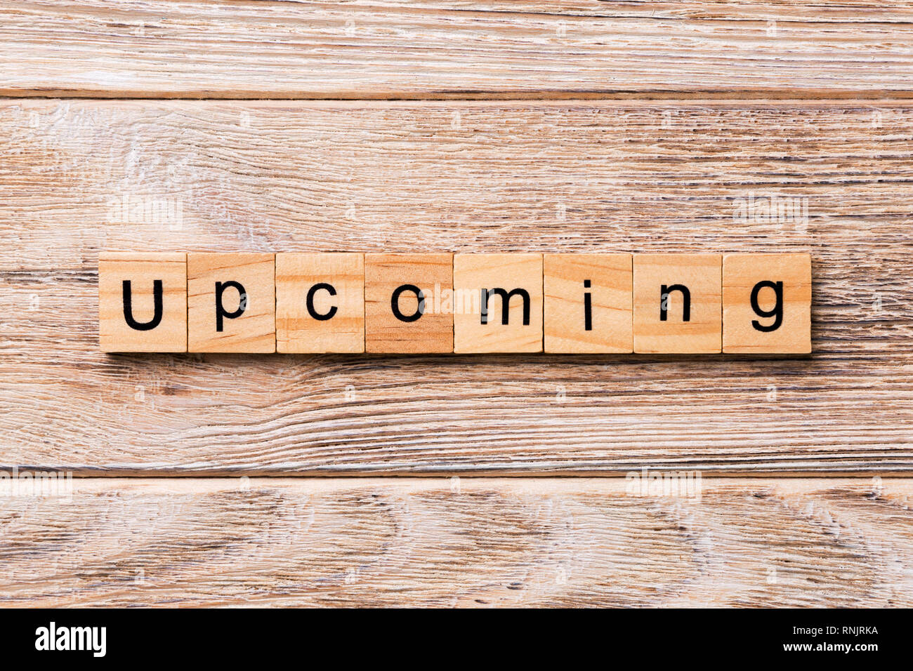 UPCOMING word written on wood block. UPCOMING text on wooden table for ...