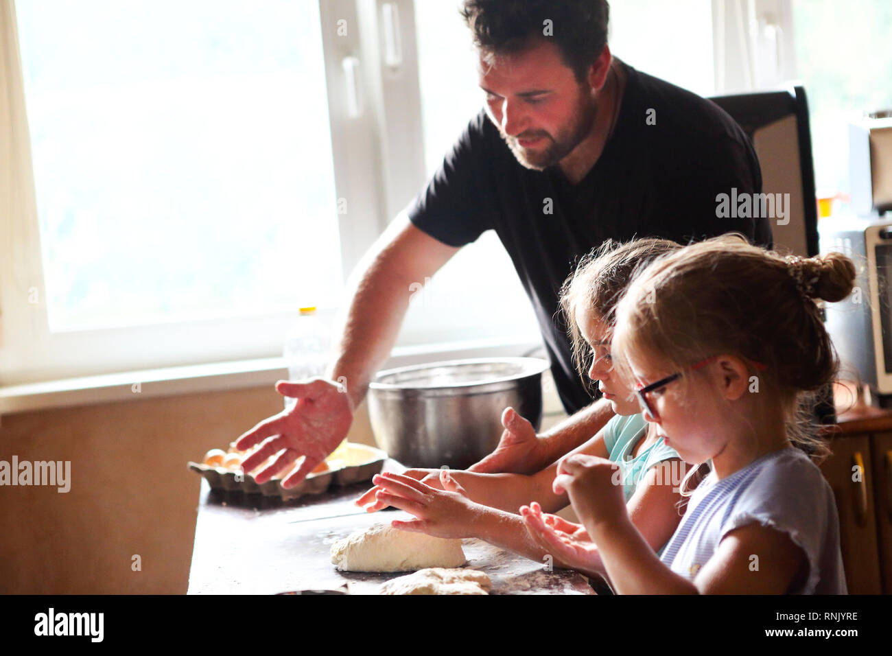 Father and his two little helpers. Children cooking homemade bread with ...