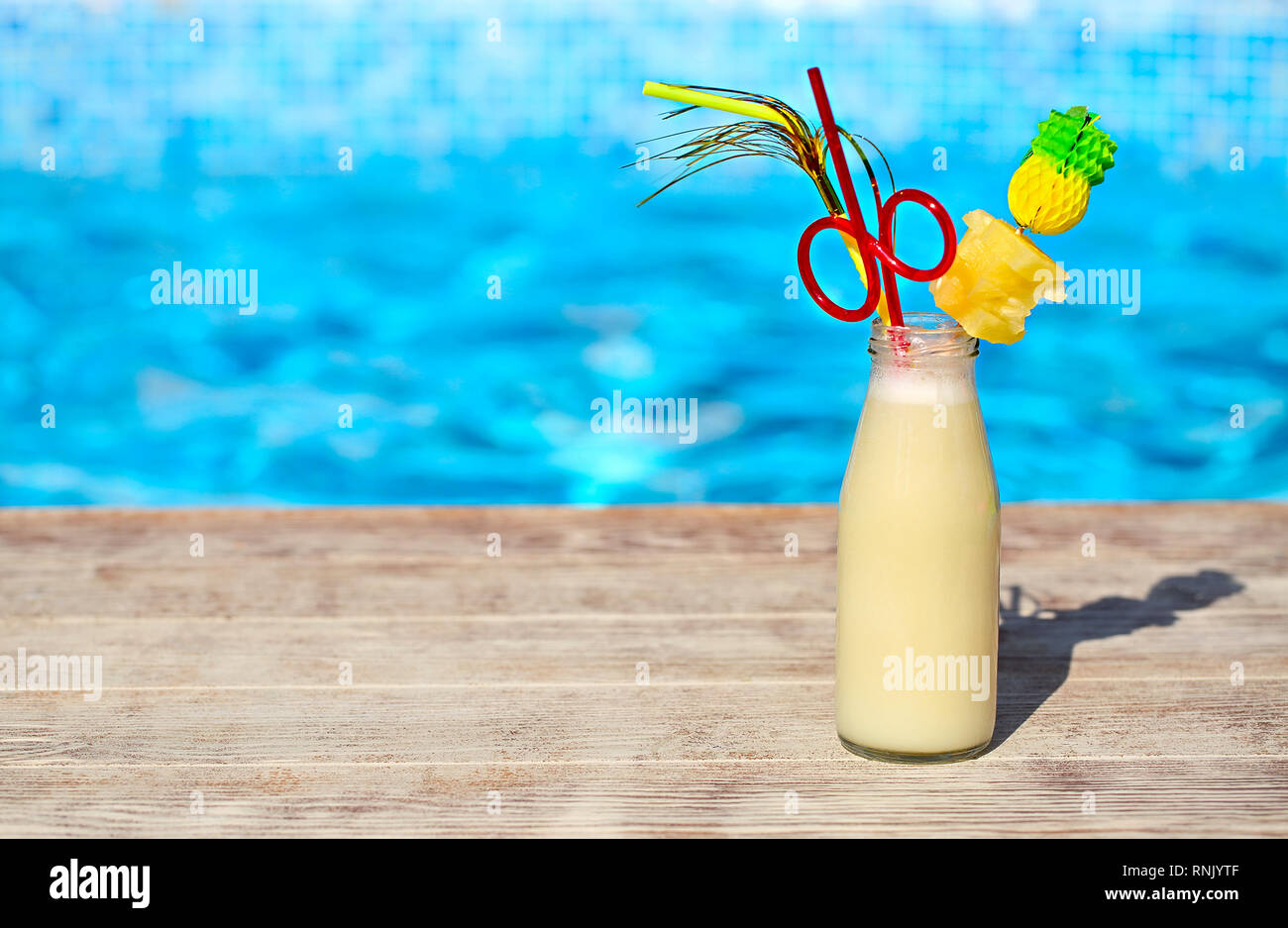 Glass of pinacolada cocktail standing on the swimming pool ledge in an ...