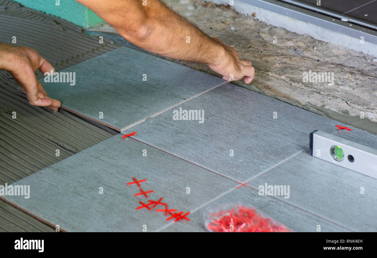 Worker installing floor tiles at home Stock Photo - Alamy