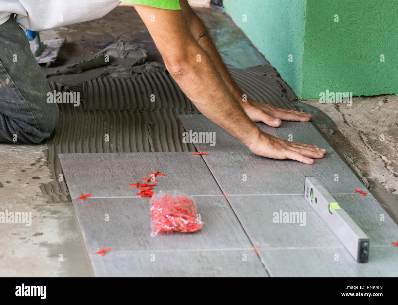 Worker installing floor tiles at home Stock Photo - Alamy
